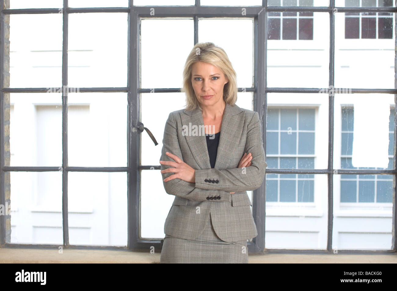 Businesswoman leaning against a window sill Stock Photo - Alamy