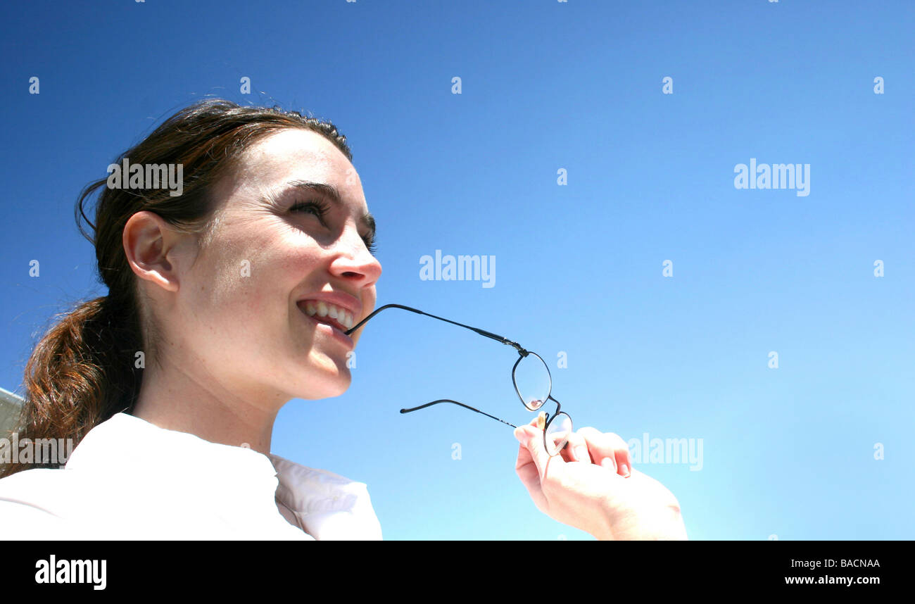 Business woman is wearing a white shirt and is biting her glasses Stock ...