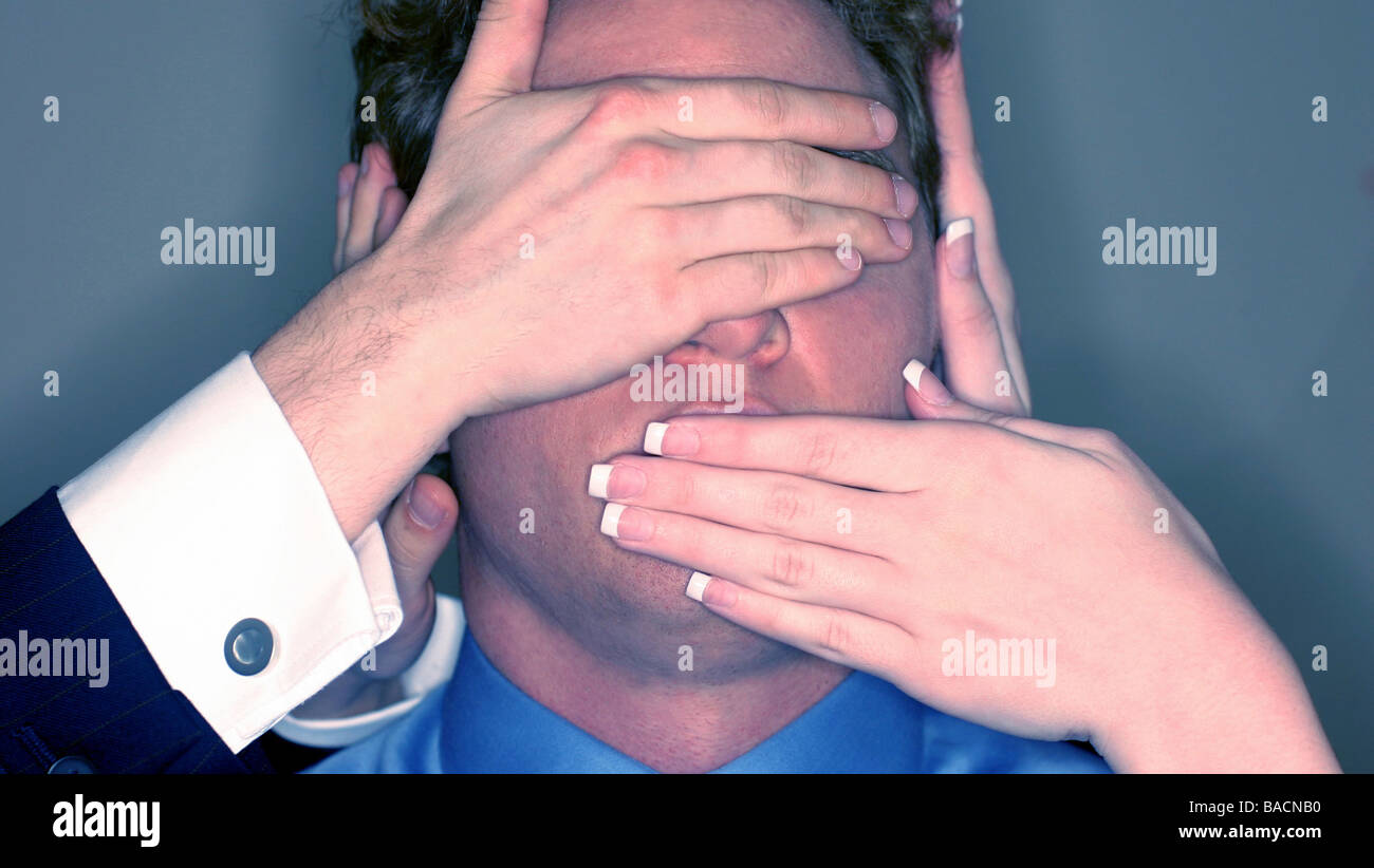Businessman's eyes and mouth is being blocked by other business people ...