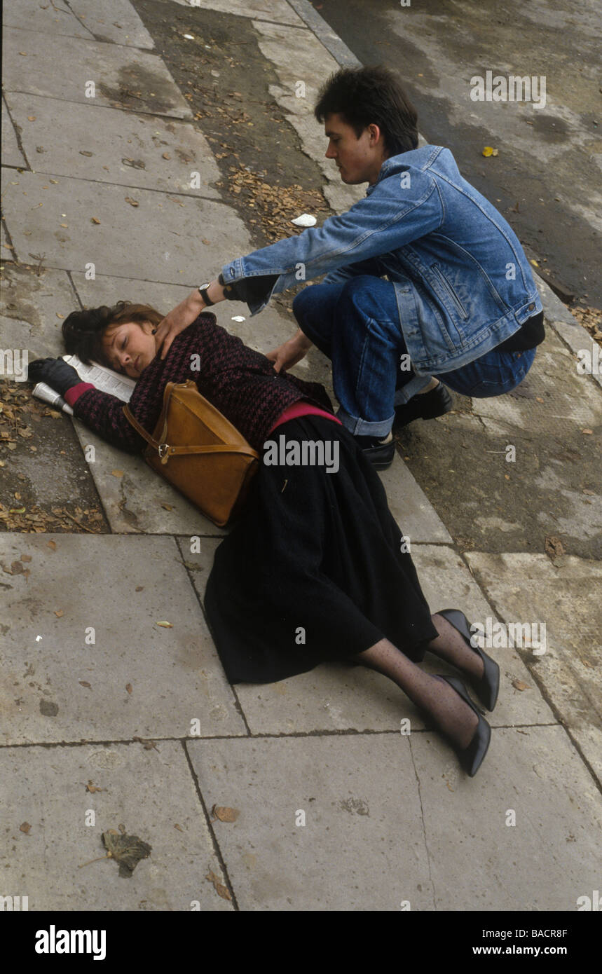 woman who has collapsed on the street being helped by a man Stock Photo ...