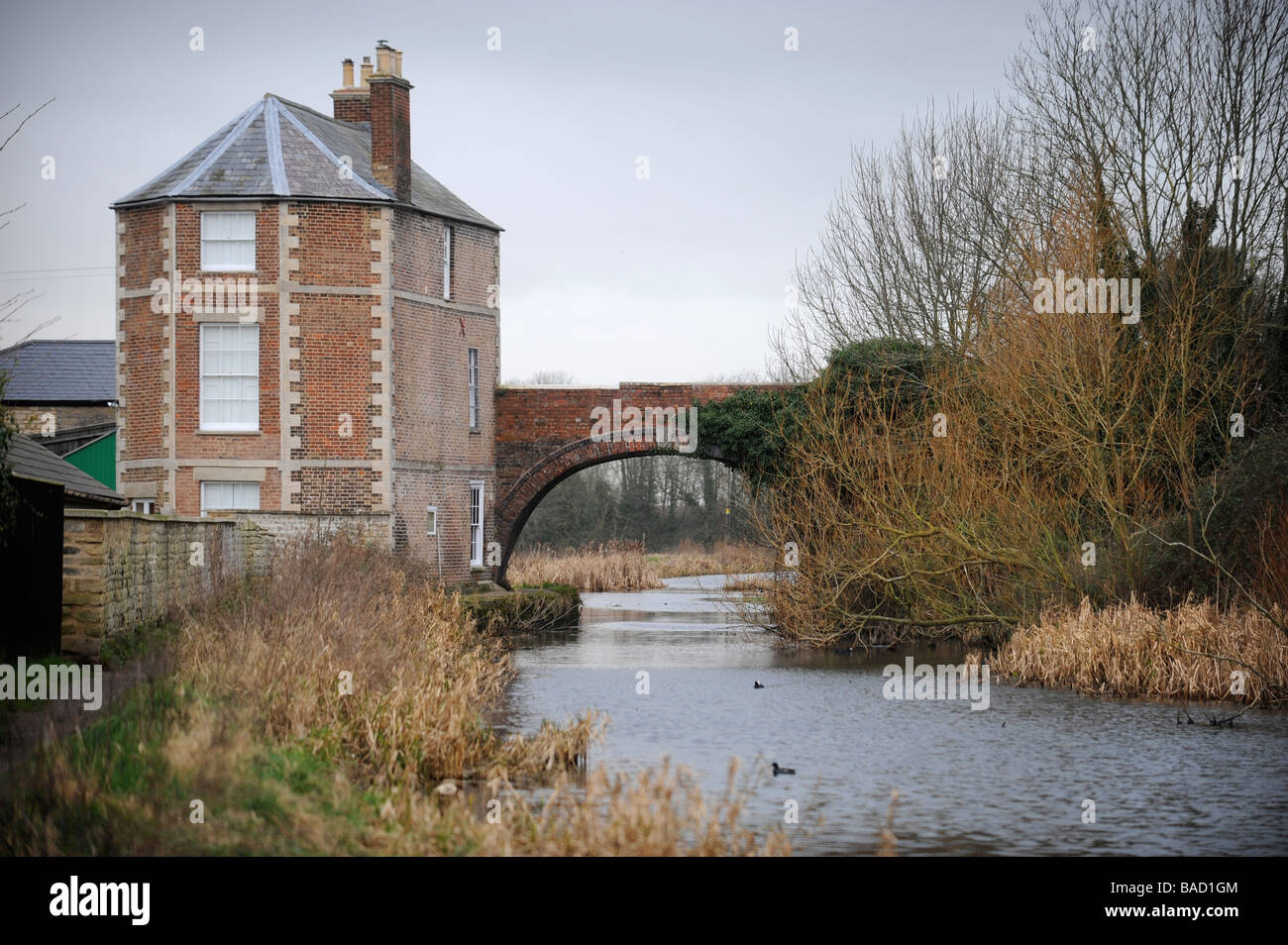 A CANALSIDE BUILDING BY AN ARCHED REDBRICK BRIDGE ON THE DISUSED ...
