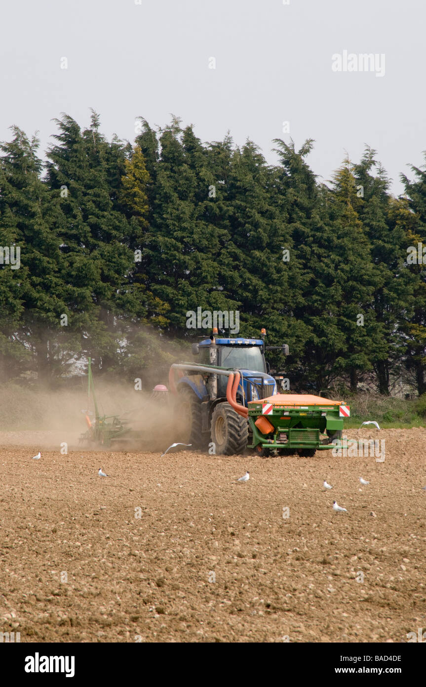 New Holland tractor with seeding attachment seeding an area of tilled ...