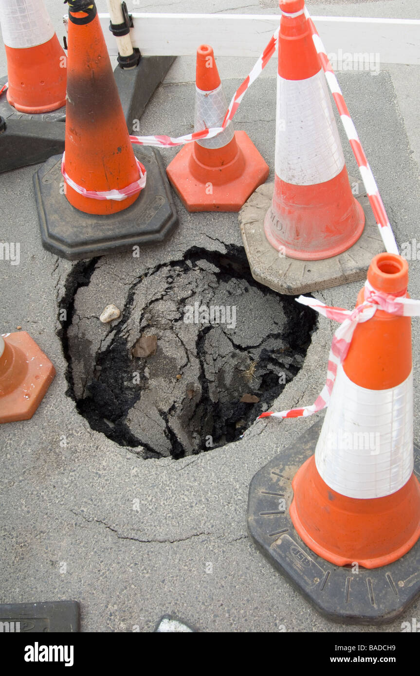 Cordoned off area of street where a hole has appeared Stock Photo - Alamy