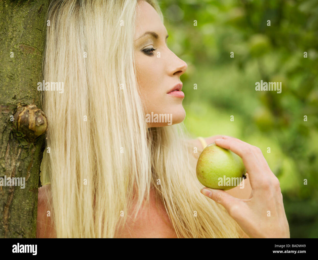 woman eating apple while leaning against tree Stock Photo - Alamy