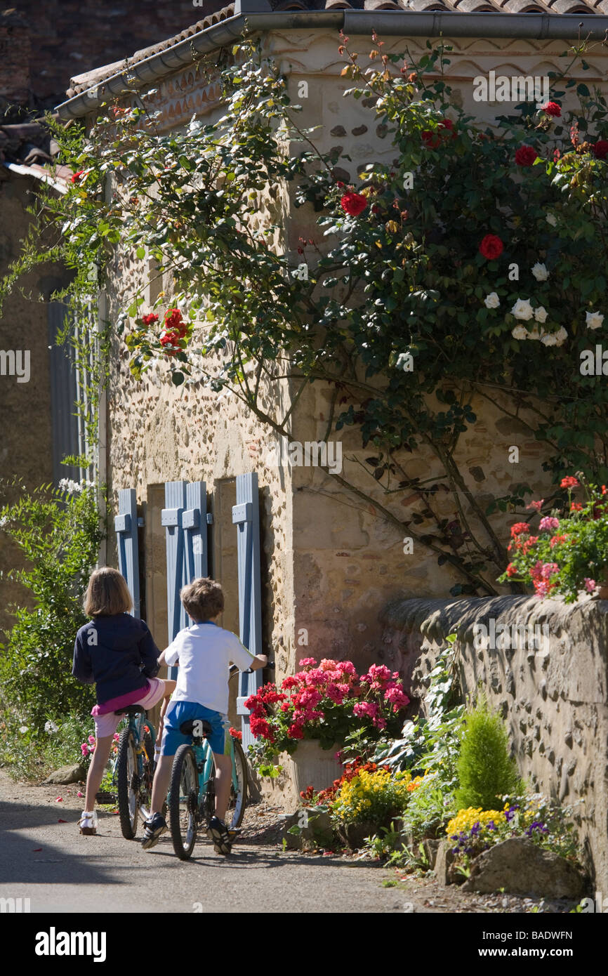 France, Landes, Pimbo, kids cycling down the flower decorated alleyways ...