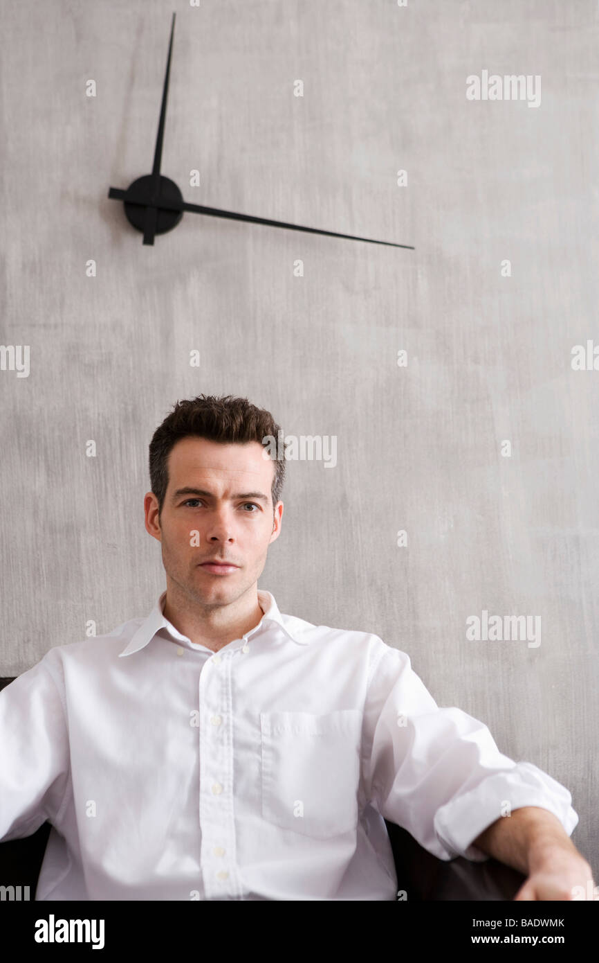 man sitting below wall clock Stock Photo - Alamy