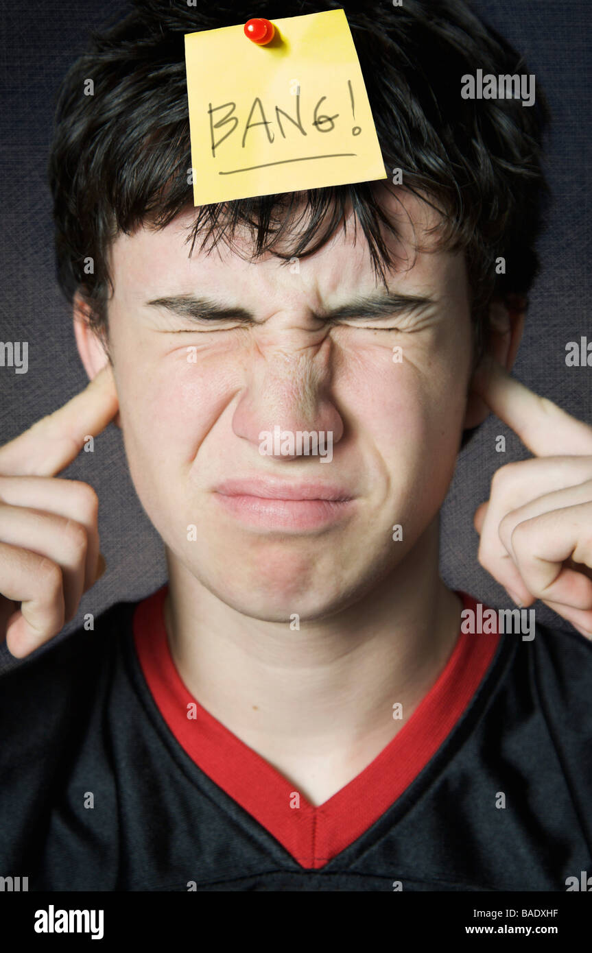 Boy Plugging Ears with Note Pinned to Forehead Stock Photo - Alamy