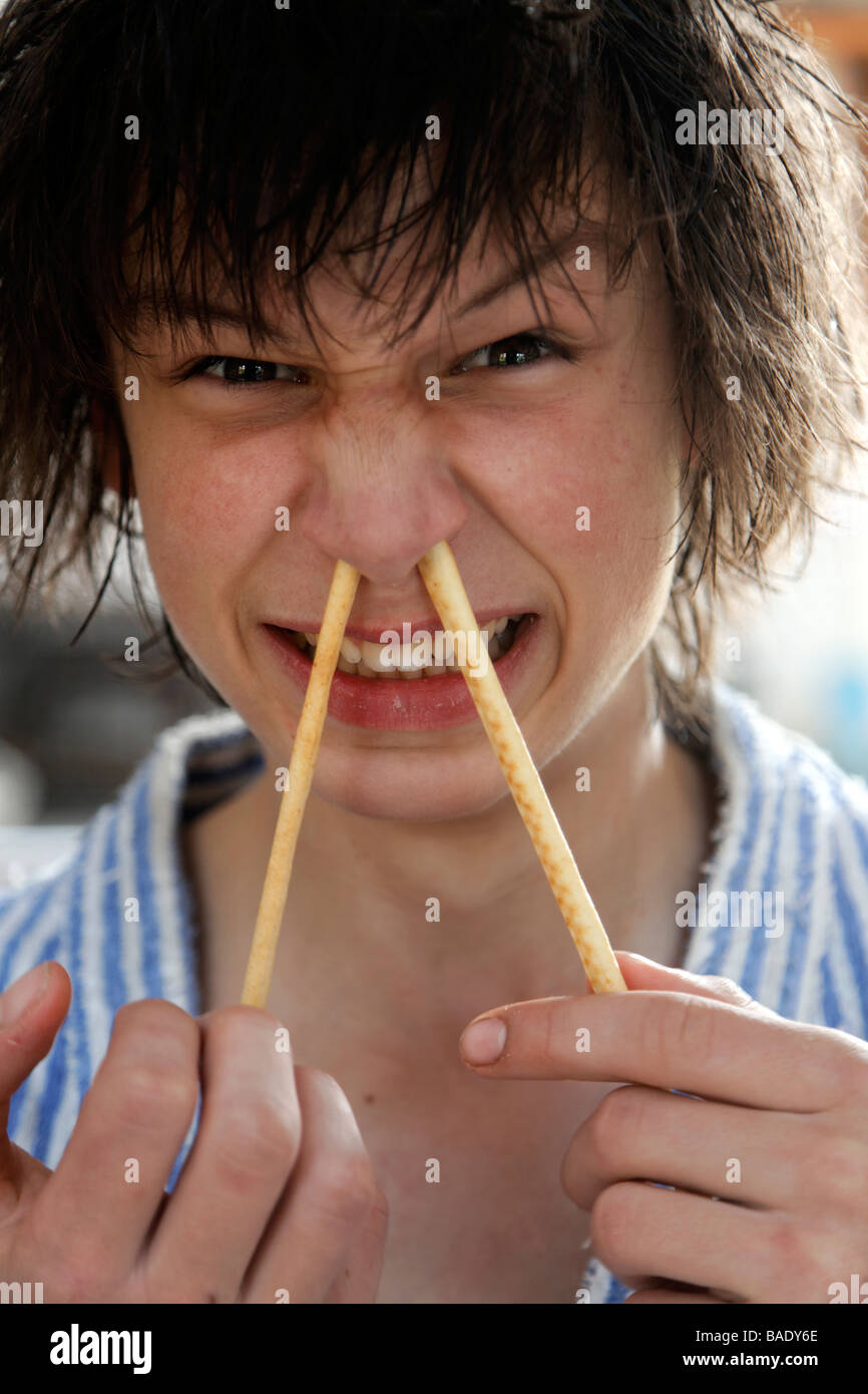 Boy fooling around breadsticks in his nostrils pulling funny face Stock ...