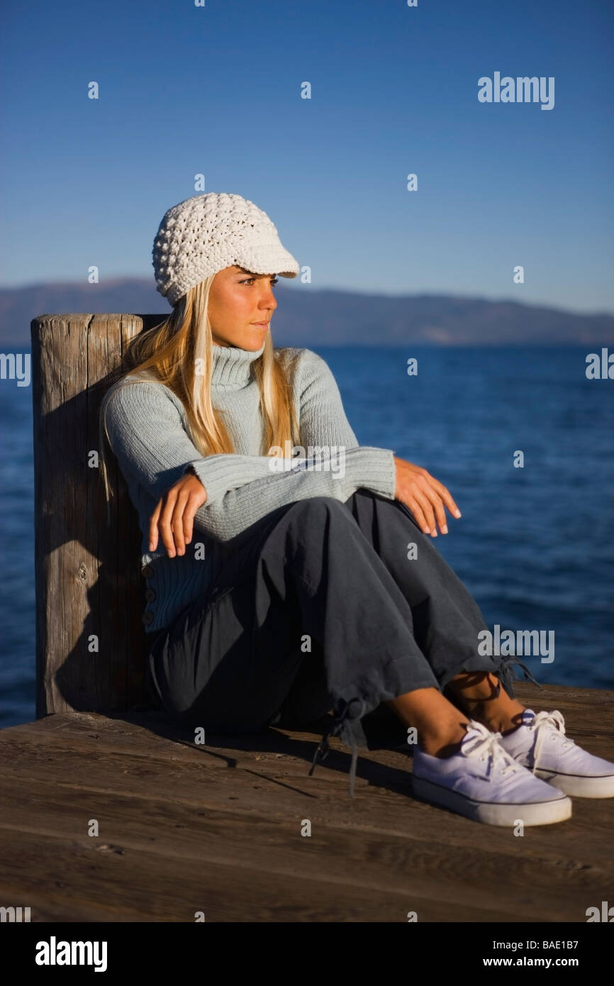 Woman Sitting On Dock by Lake Stock Photo - Alamy