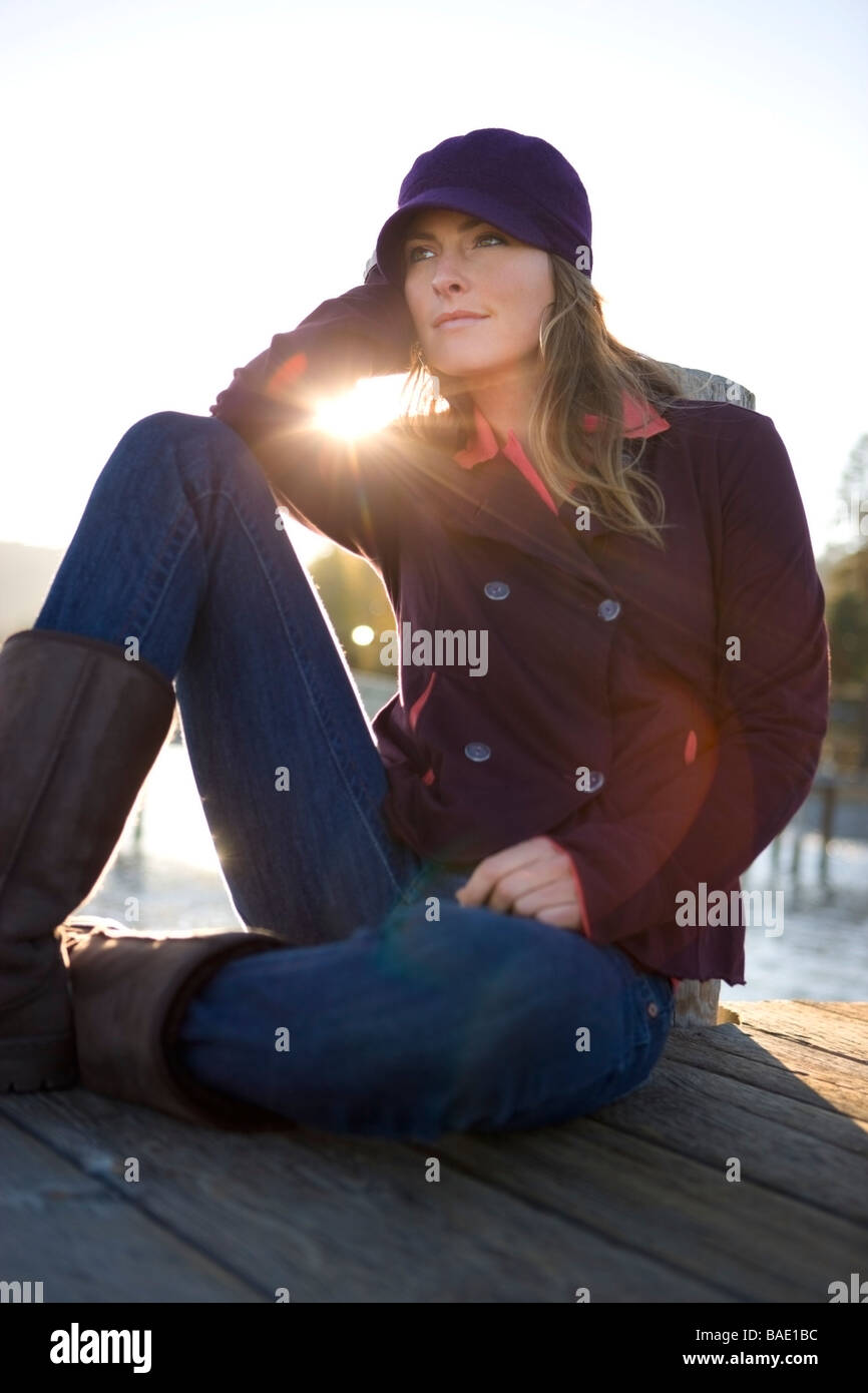 Woman Sitting On Dock by Lake Stock Photo - Alamy