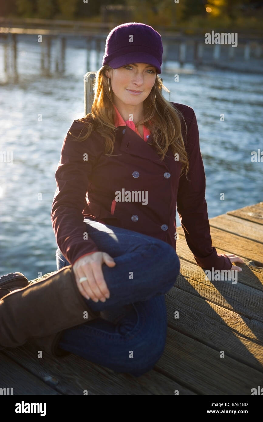 Woman Sitting On Dock by Lake Stock Photo - Alamy