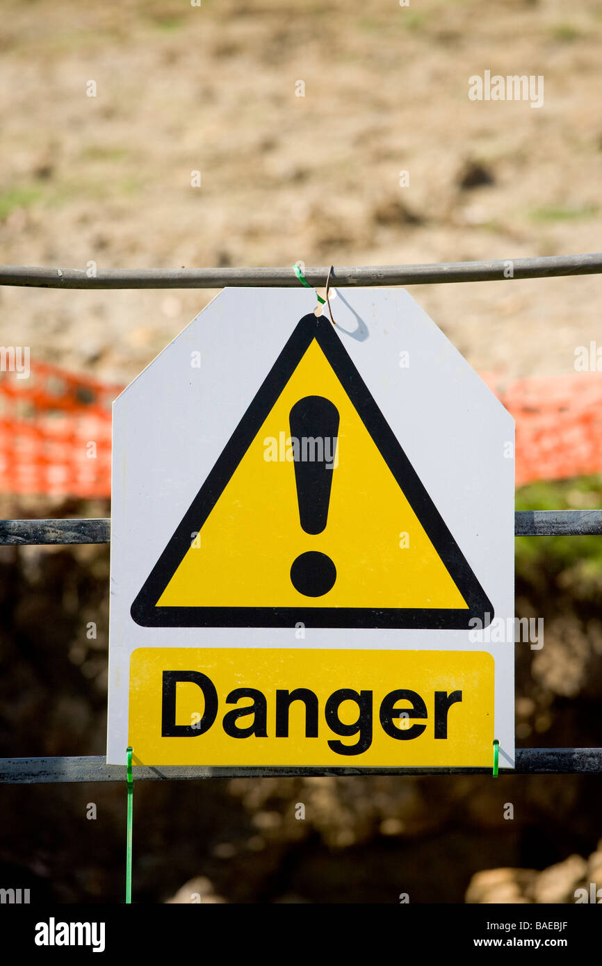 Danger sign mounted in railings with a hole in the ground and orange ...