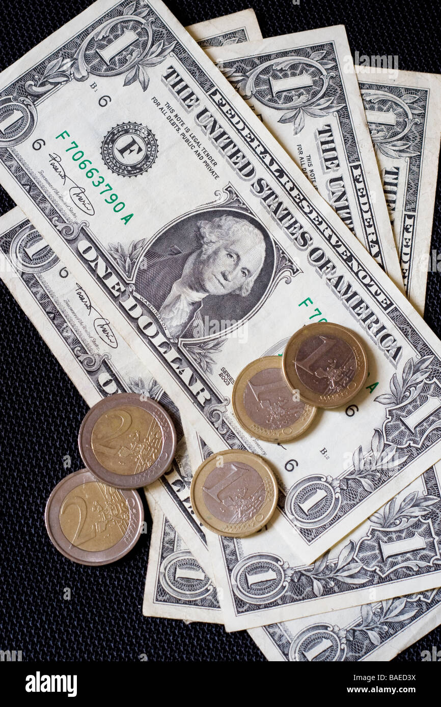 Some Euros coins scattered on a pile of one dollar bills on a black background Stock Photo - Alamy