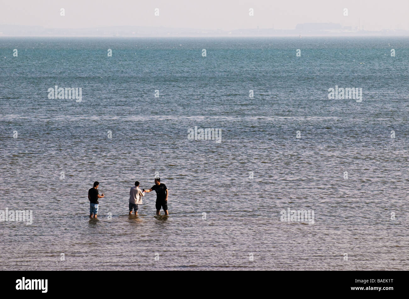 Three people standing in the sea at Southend on Sea in Essex. Photo by ...