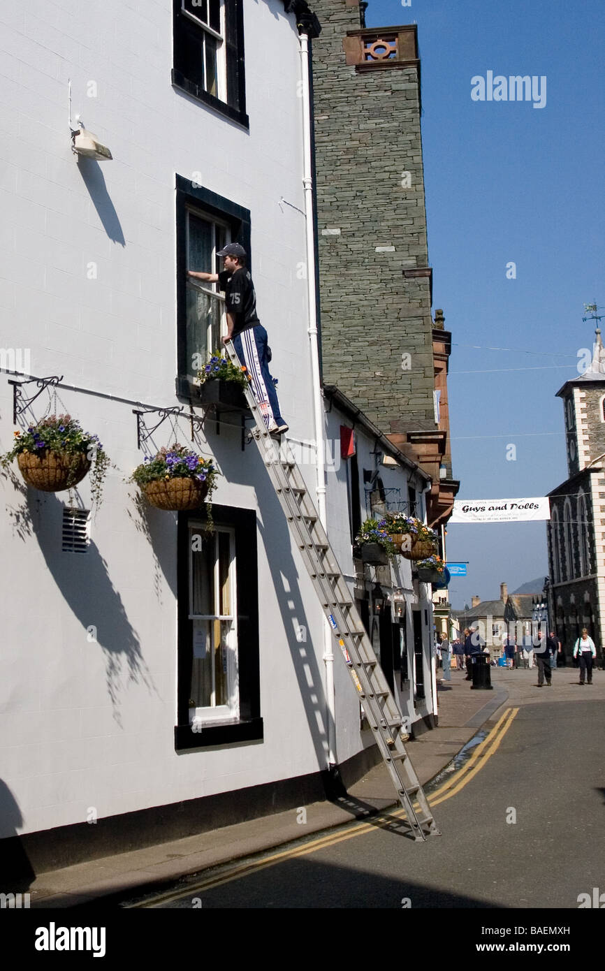 Window Cleaner up a ladder in Keswick Lake District Cumbria England ...