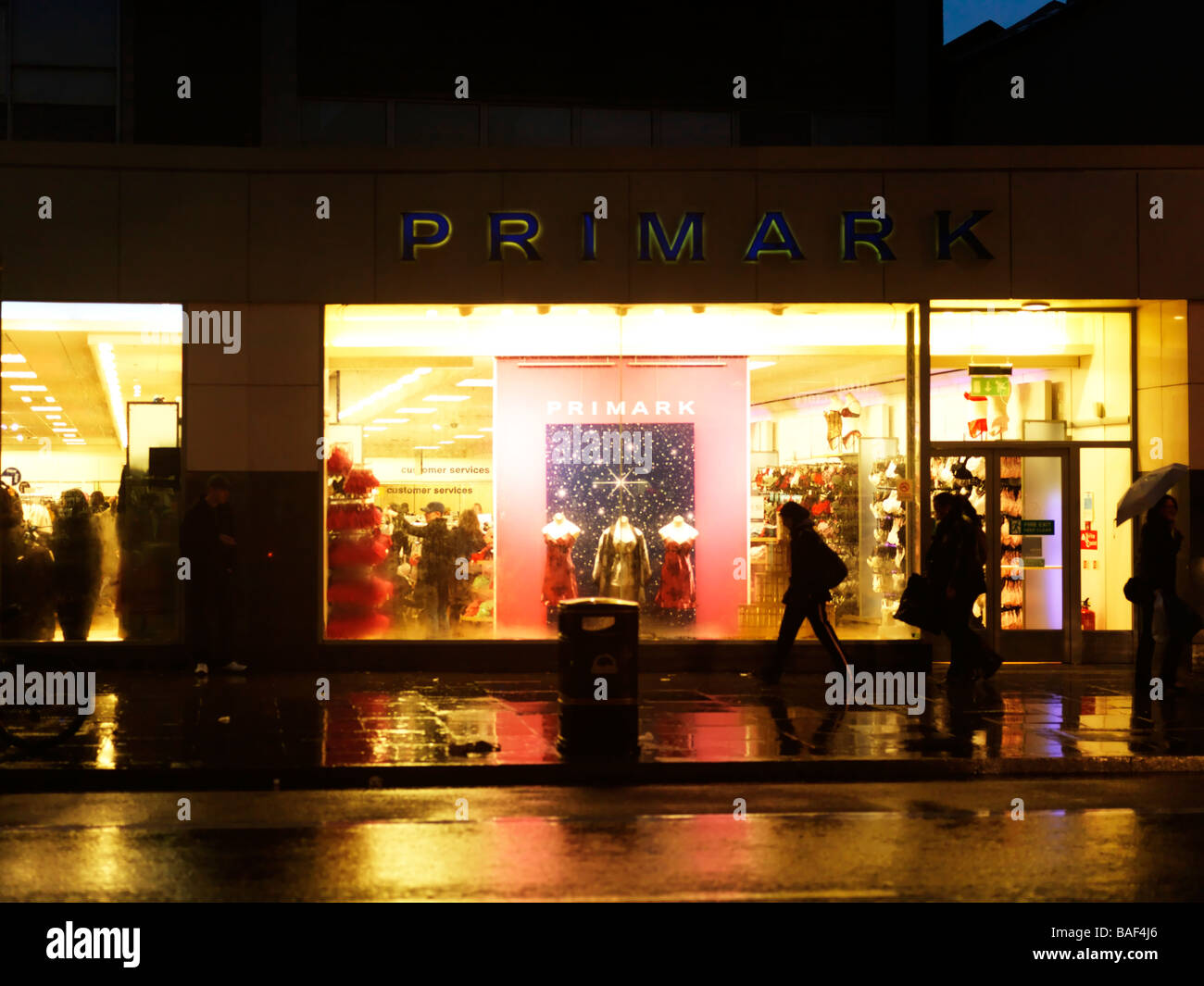 Shoppers in the rain Primark Tooting High Street at night London Stock ...