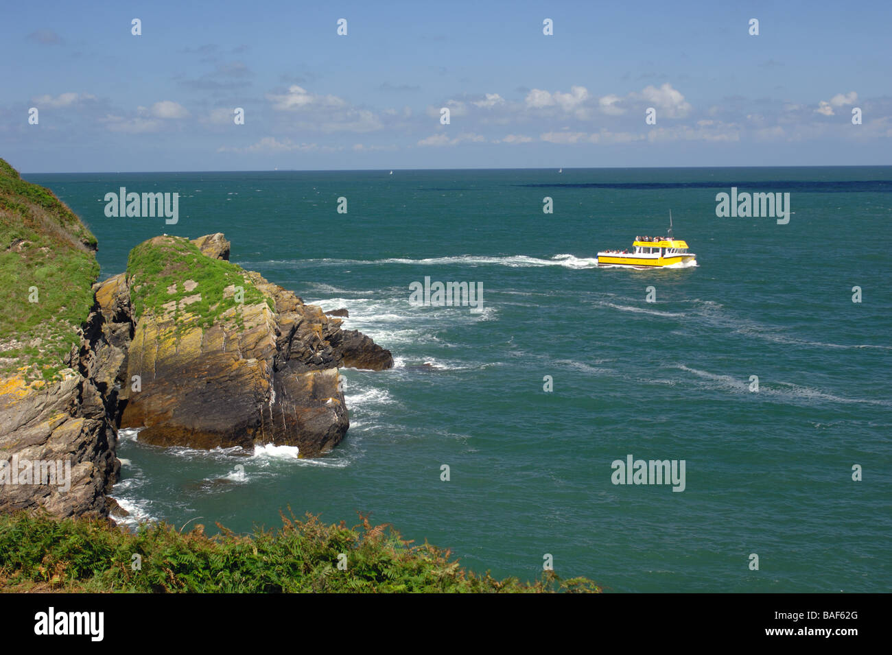 A tourist sightseeing boat on the north Devon coast enters Widmouth bay ...