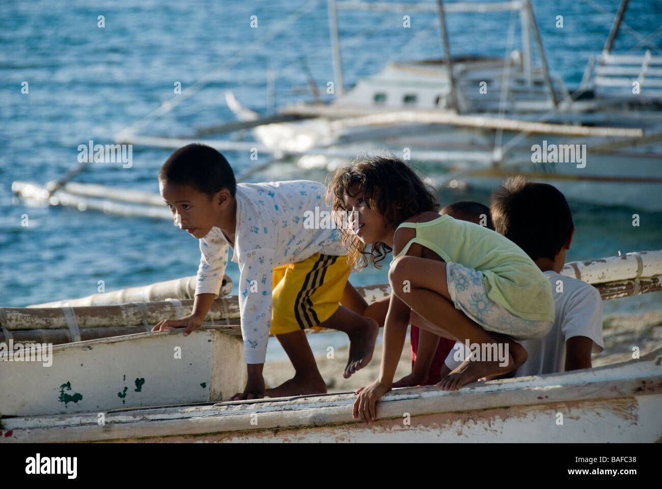 Children playing in a boat on the beach at Apo Island, Philippines ...
