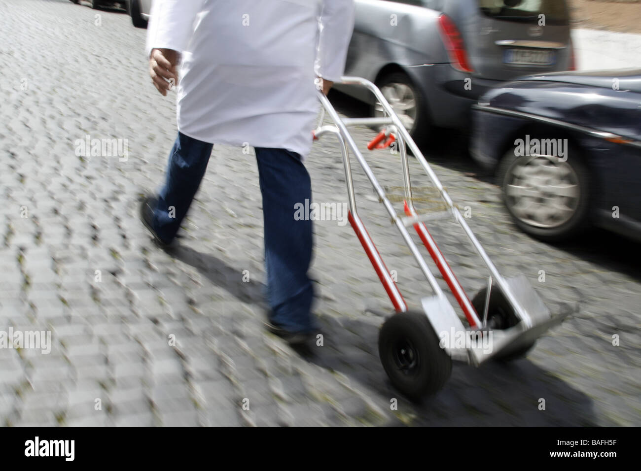 one man pulling empty goods trolley on street in city town Stock Photo ...