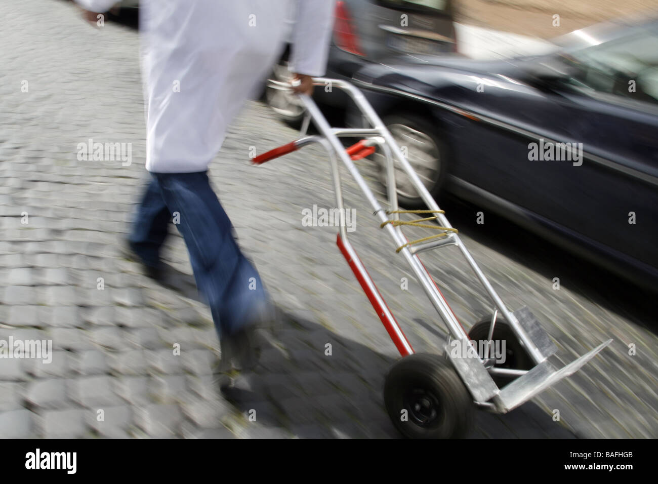 one man pulling empty goods trolley on street in city town Stock Photo ...