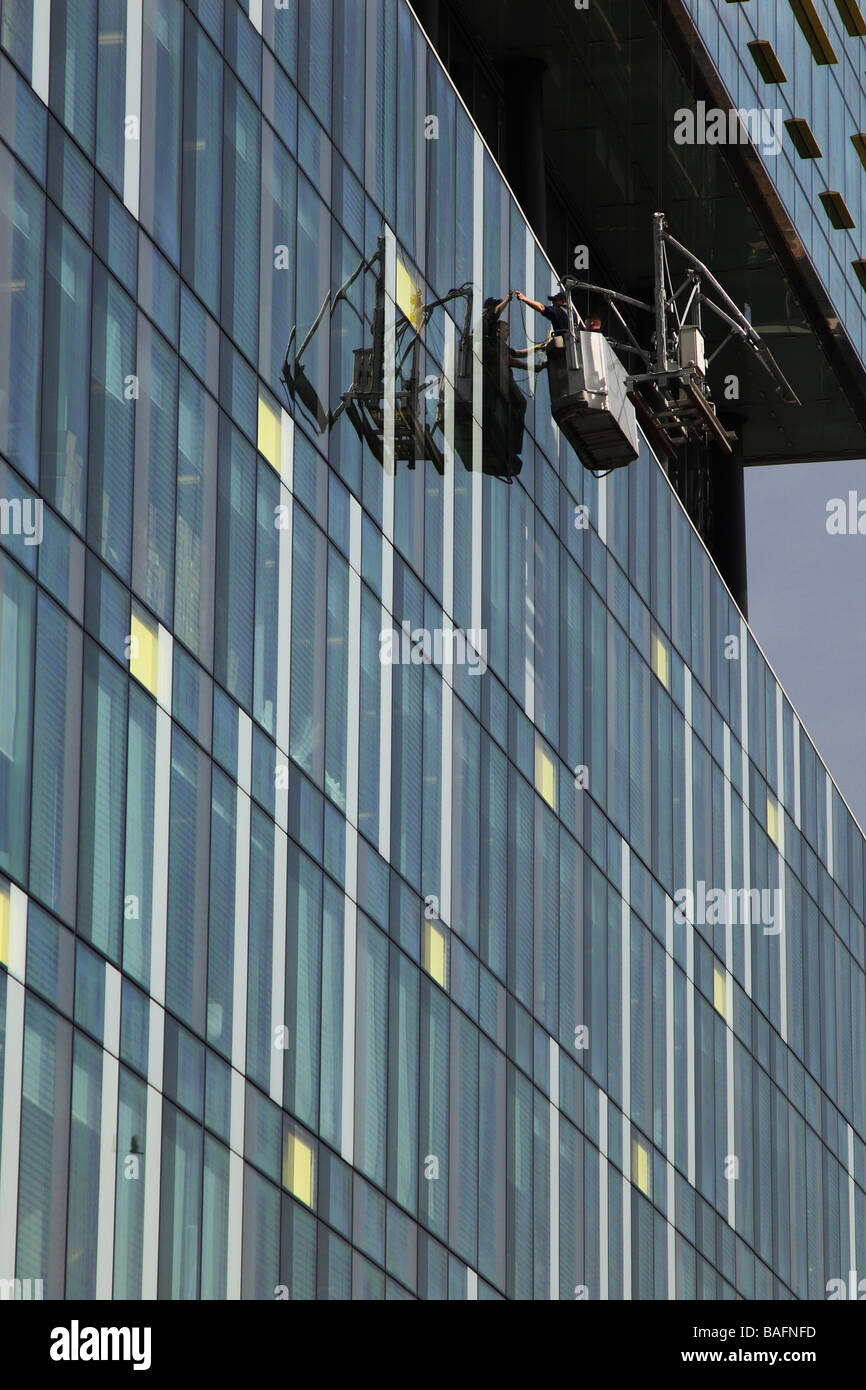 Window cleaners in cradle suspended from one of London's glass towers ...