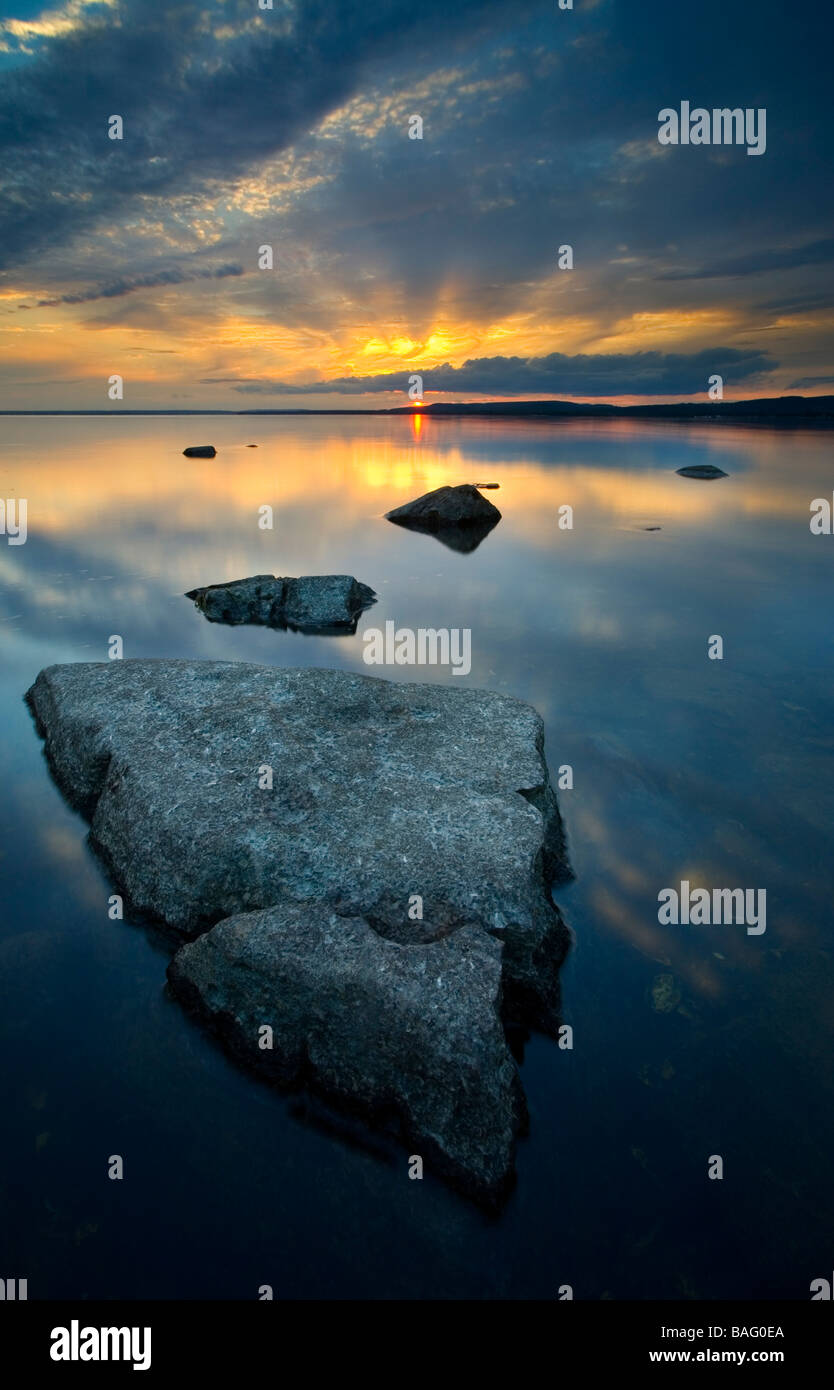 A simplistic coastal landscape of a beautiful sunset over a lake with ...