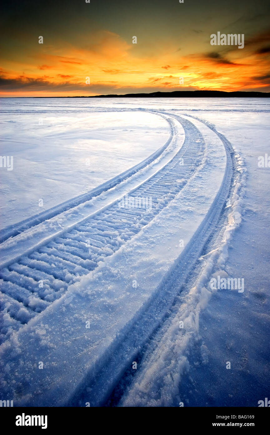 A Canadian Winter landscape of snowmobile tracks on a frozen lake ...