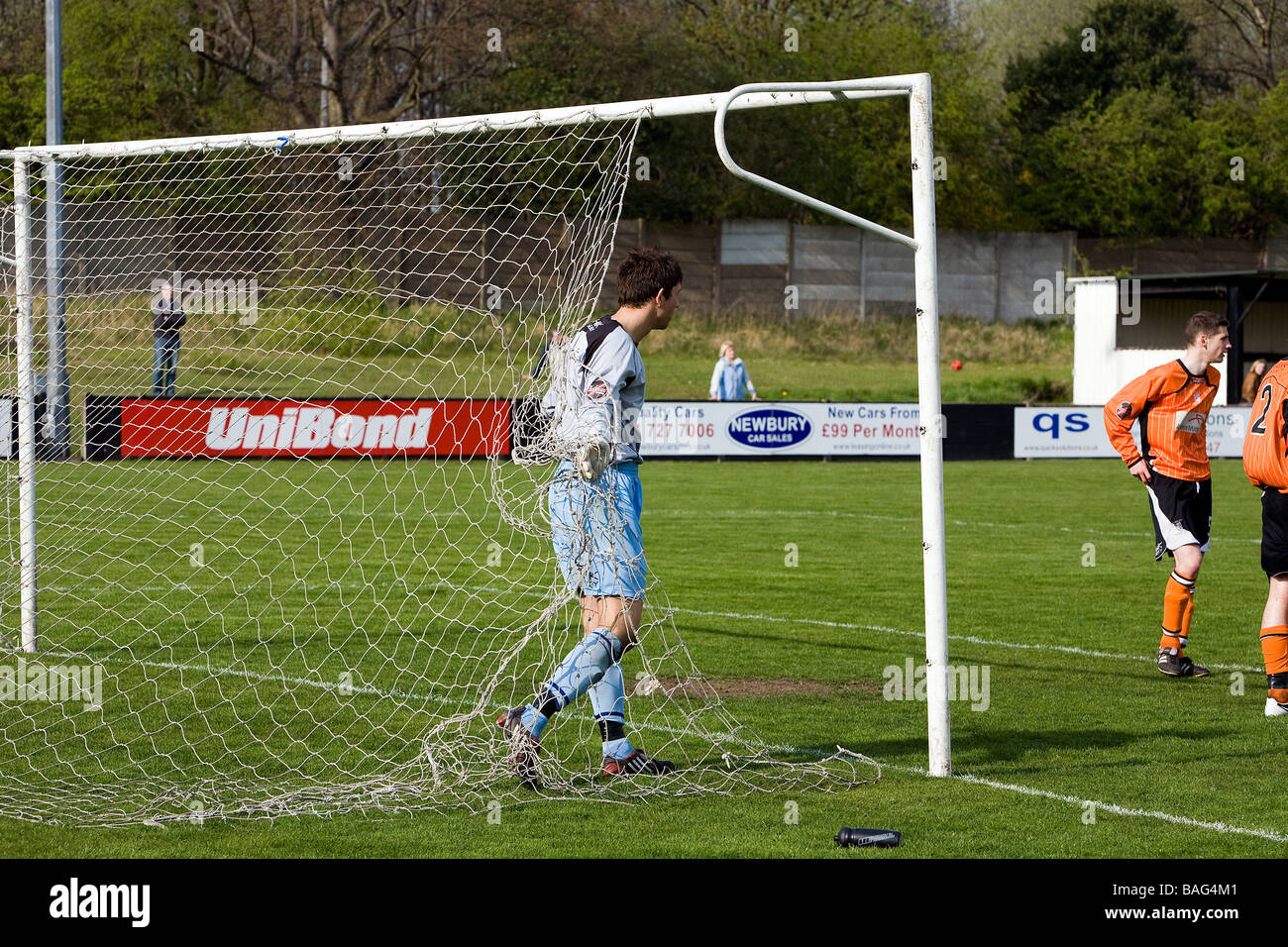 The goal keeper holds the broken net which he has just fallen into ...