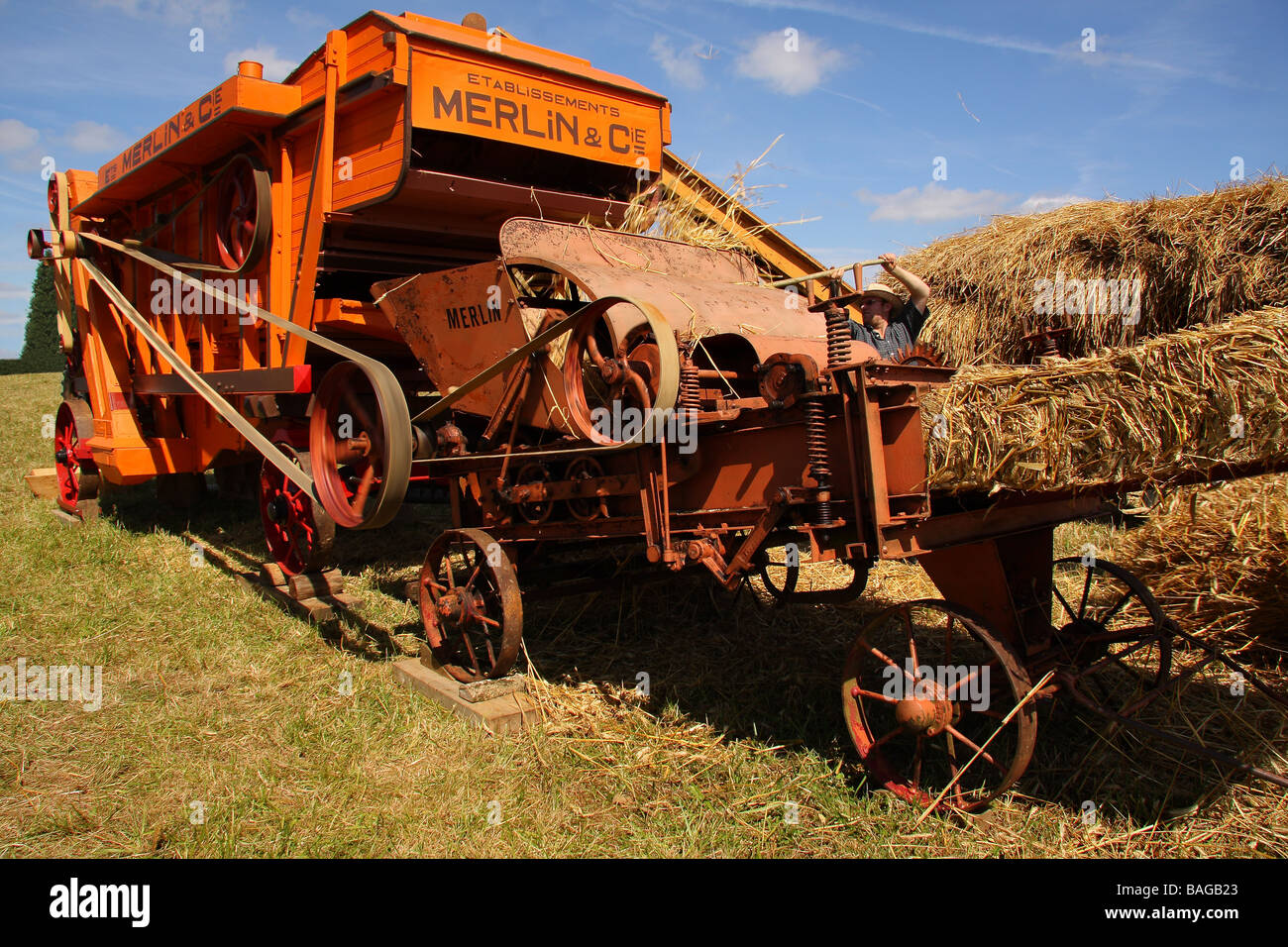 An old French belt driven threshing machine painted in orange in a ...