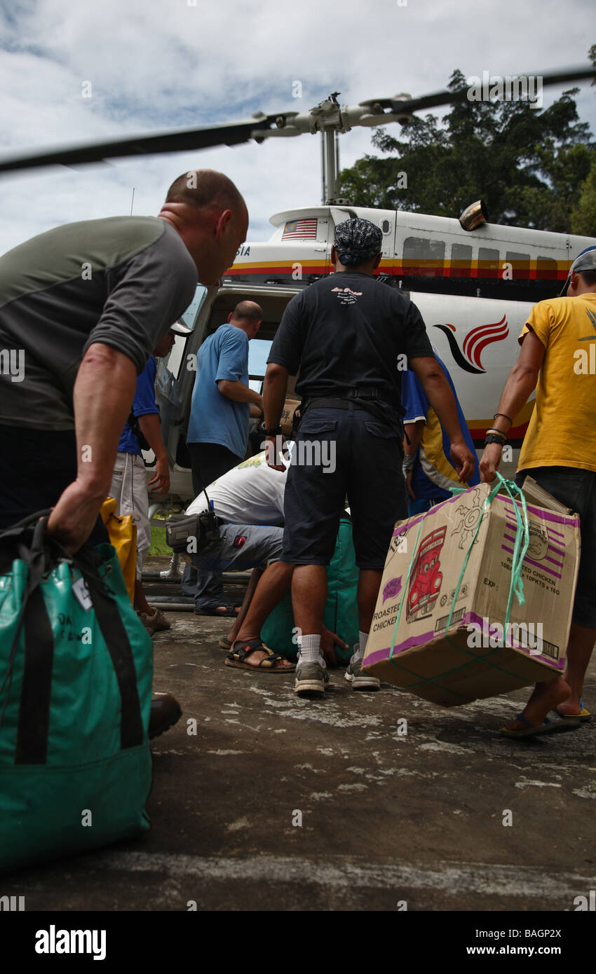 Men loading supplies into a helicopter before it leaves and flies into ...