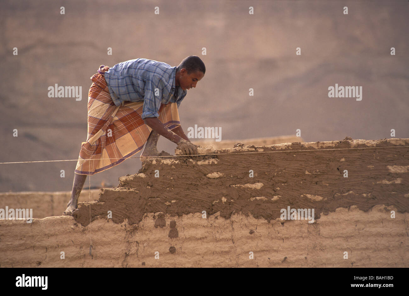 Yemen, Hadramawt Governorate, Wadi Hadramawt, man building house with ...
