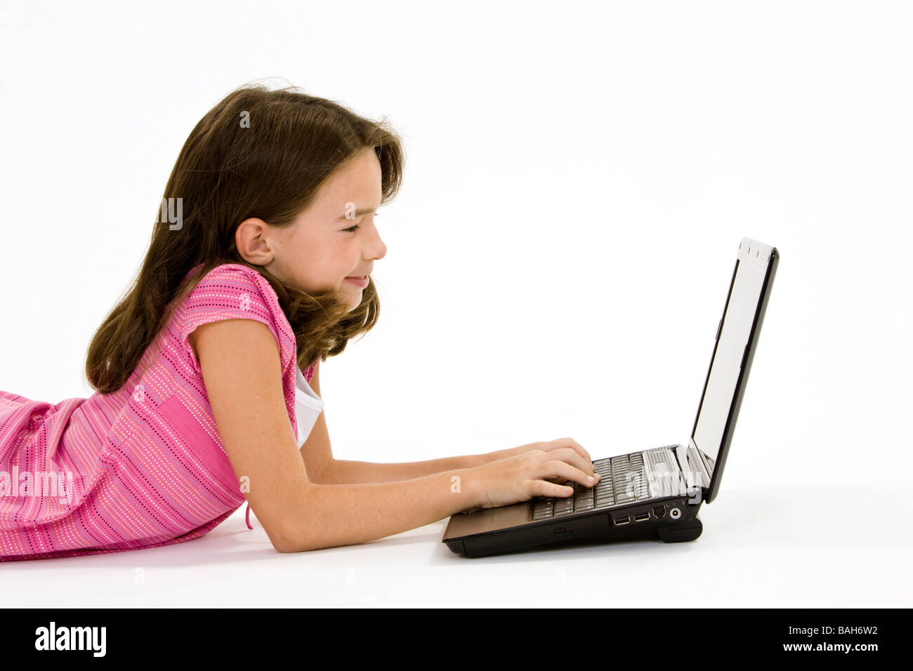 Child laying on a white background working on laptop computer Stock ...