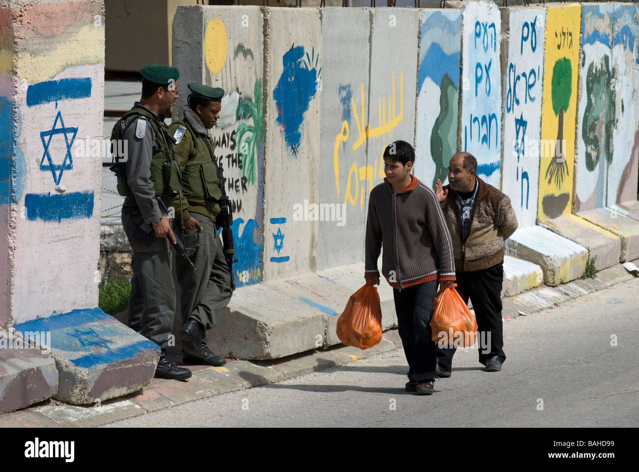 Palestinian men walking along concrete slabs separating Palestinian ...