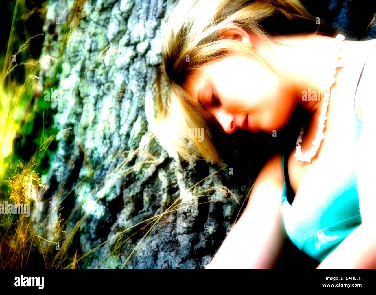 A young woman lying against a tree, eyes closed Stock Photo - Alamy