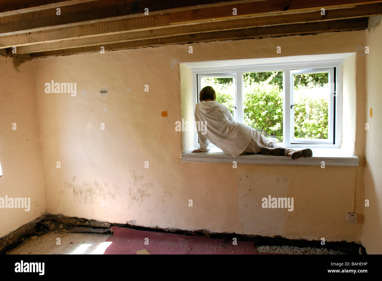 A woman paints a window in a Cornish cottage being totally re-built ...