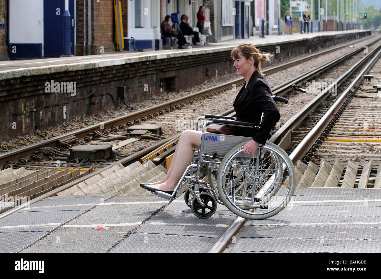 Disabled woman using a level crossing to reach the opposite station ...