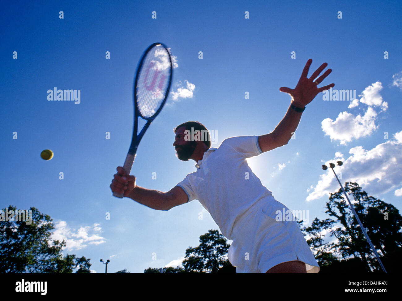 Male tennis player hitting the ball with a racket Stock Photo - Alamy