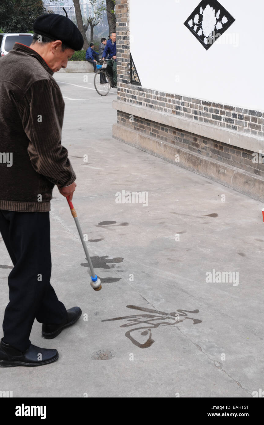 Old Chinese man practicing calligraphy with a water brush. A common ...