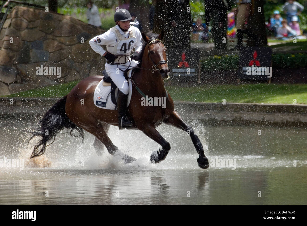 Rider and horse splashing through water hazard during competition in ...