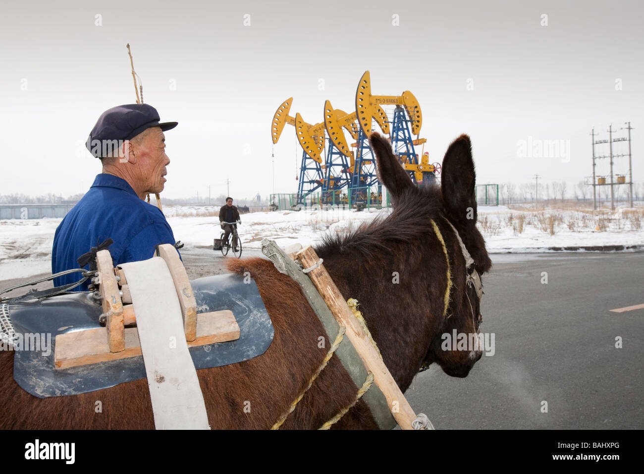 A peasant farmer and his donkey cart infornt of nodding donkey oil ...