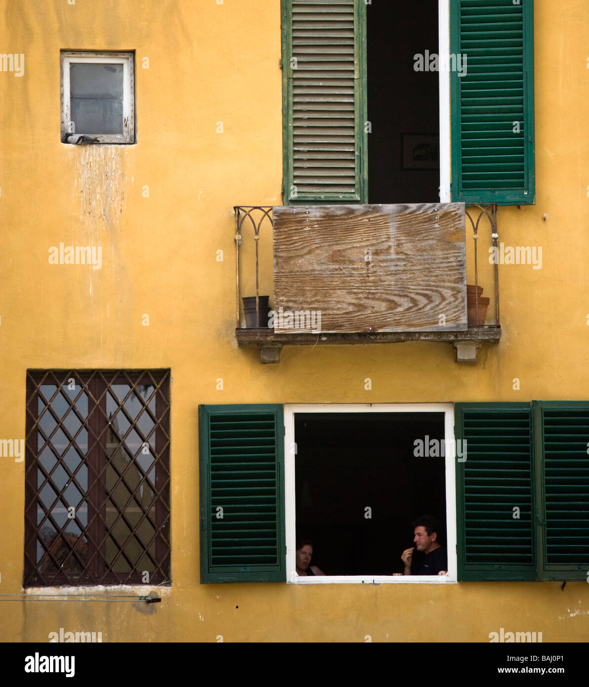 A couple sitting having lunch in a shutterd window in the Piazza ...