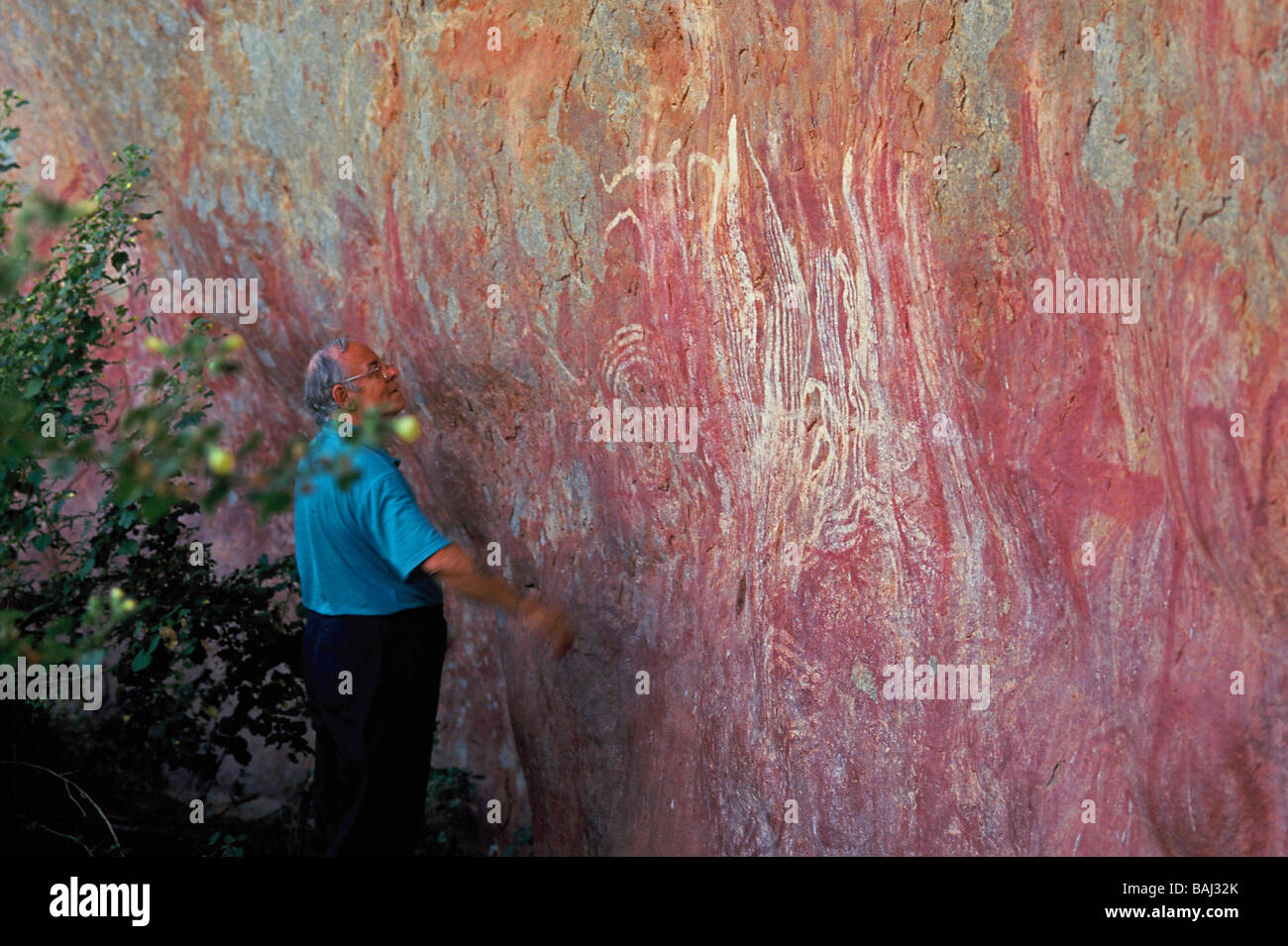 Man studying aboriginal wall paintings at Walga rock Western Australia ...