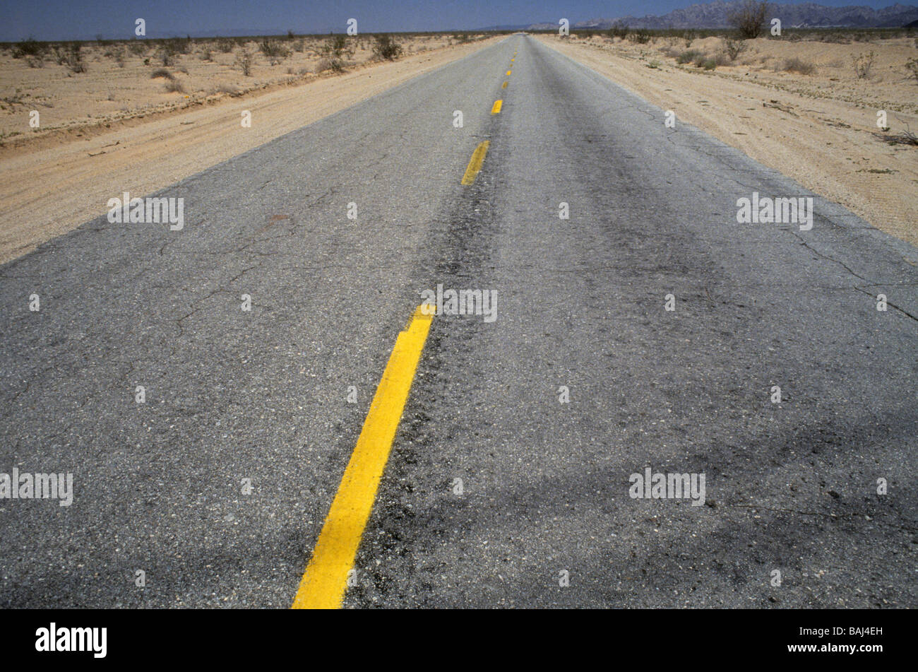 road desert highway yellow center stripe divide alone desolate arid ...