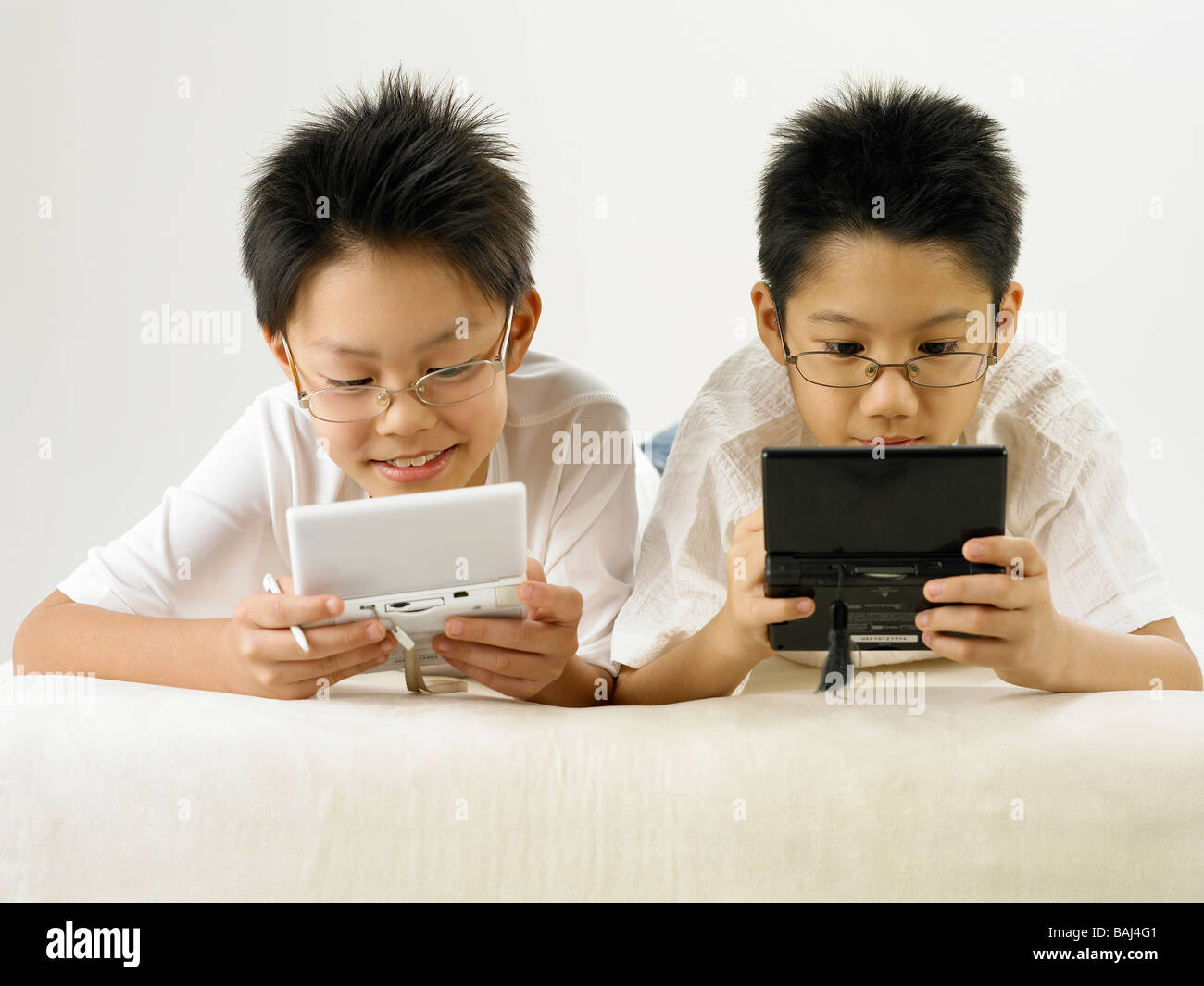 two friend palying handheld video game side by side Stock Photo - Alamy