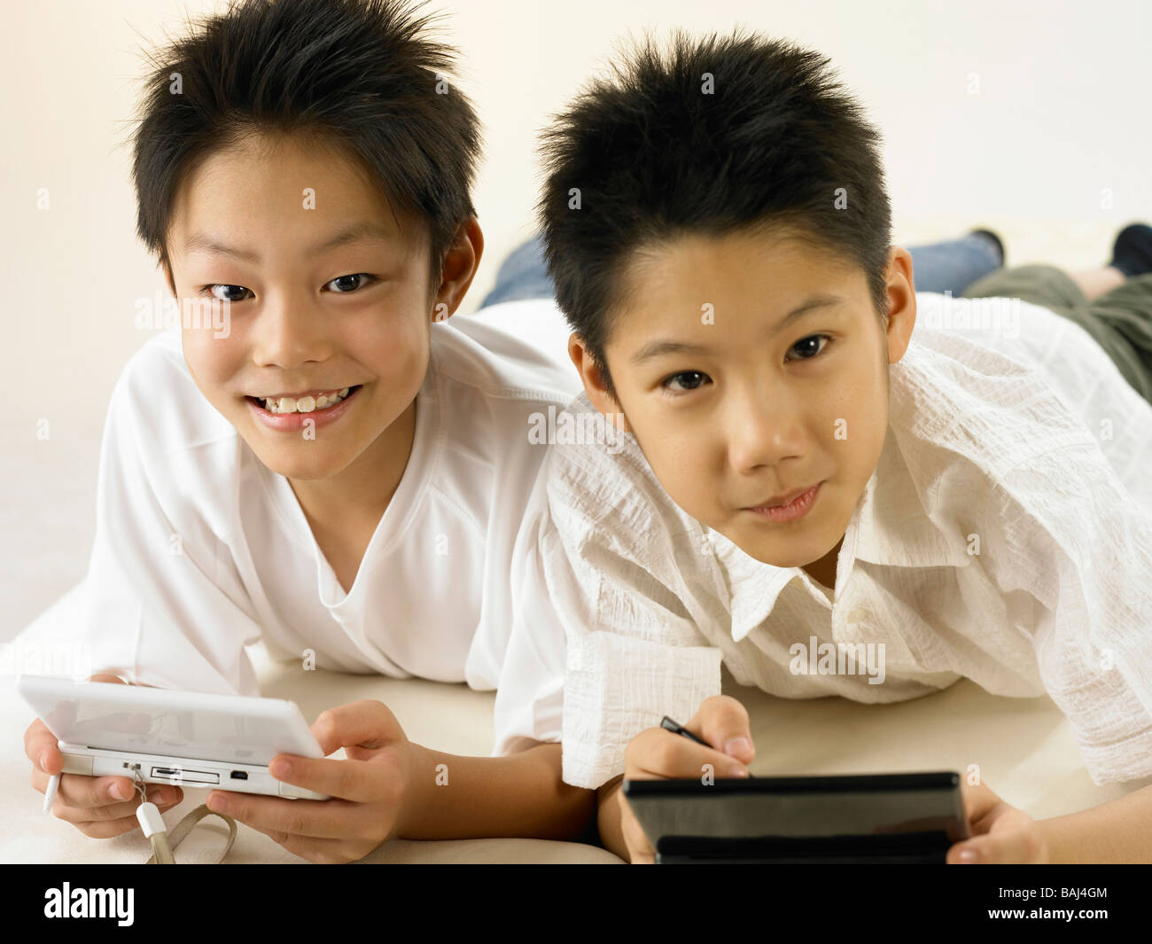 two friend playing hand held video game side by side Stock Photo - Alamy