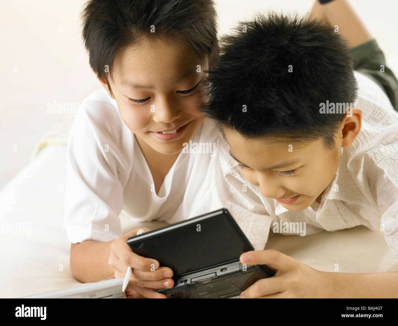 two friend playing hand held video game togethar Stock Photo - Alamy