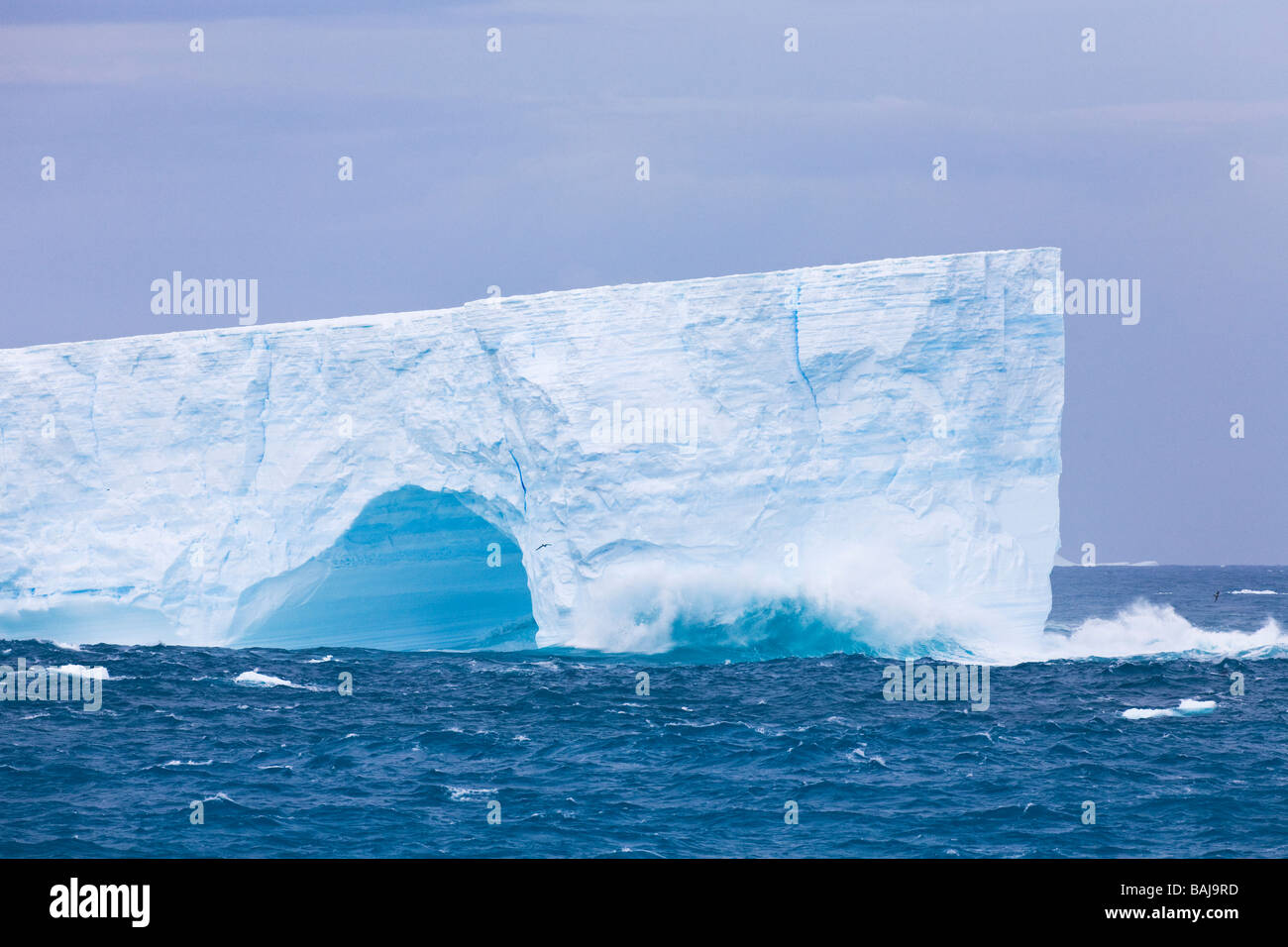 Ice arch in blue tabular iceberg in stormy weather Southern Ocean ...