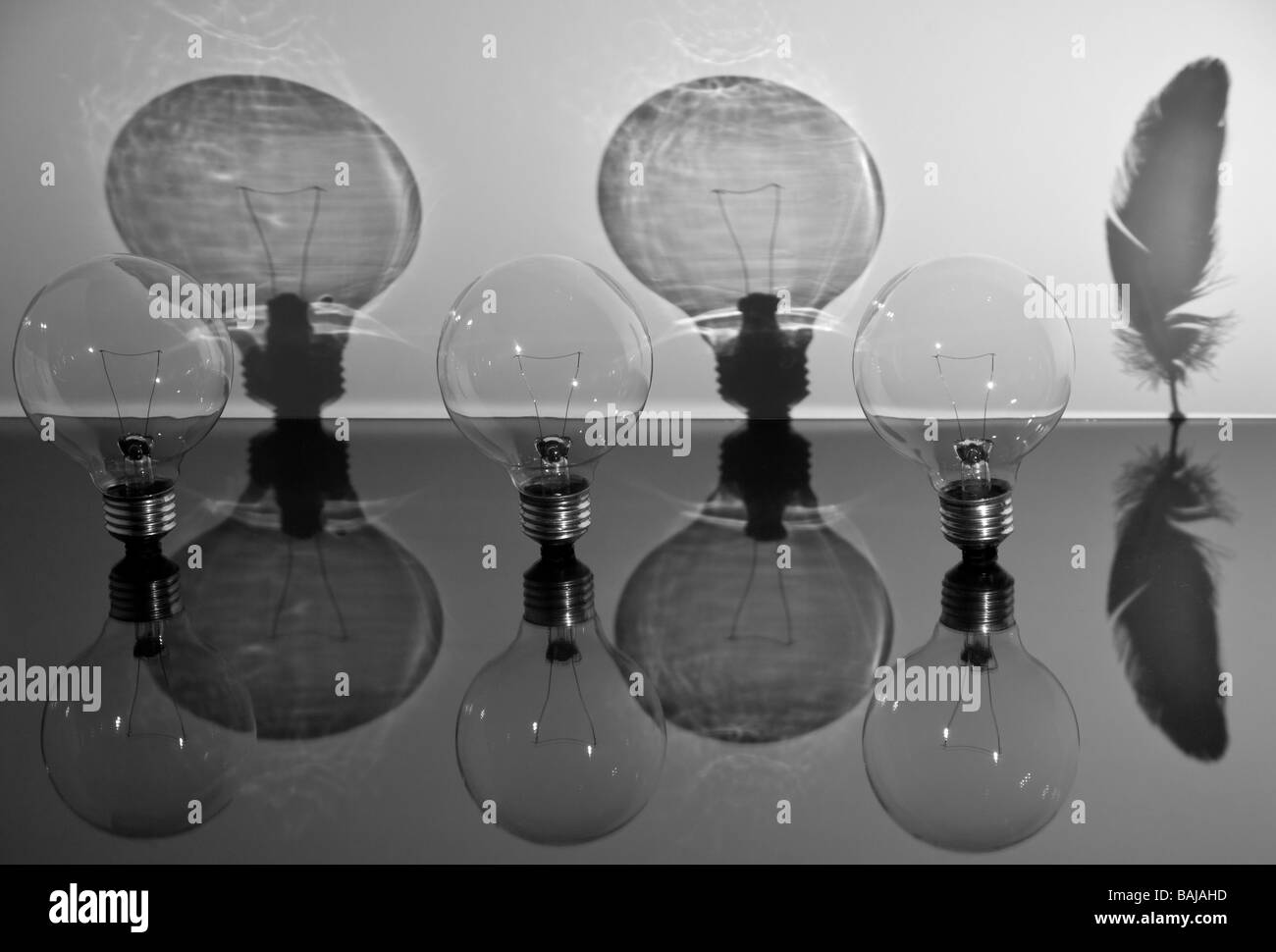 Three light bulbs, one casts a shadow as a feather Stock Photo - Alamy