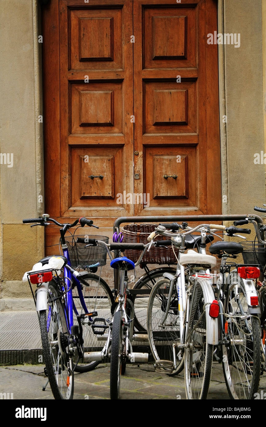 Florence, Italy; Bikes parked at a bike rack outside wooden doors Stock ...