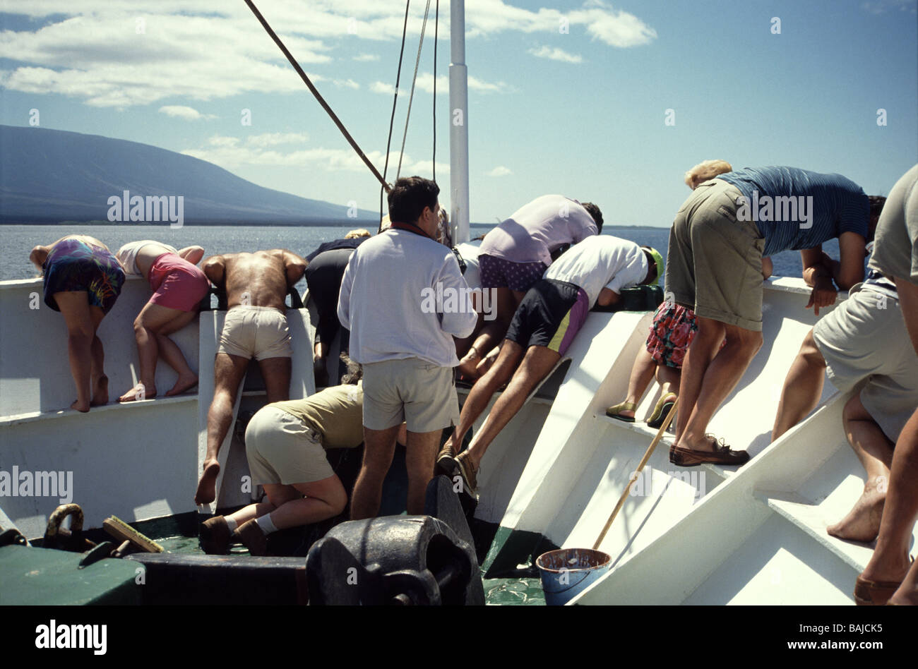 Galapagos Islands. People Dolphin watching from the bows of a cruise ...